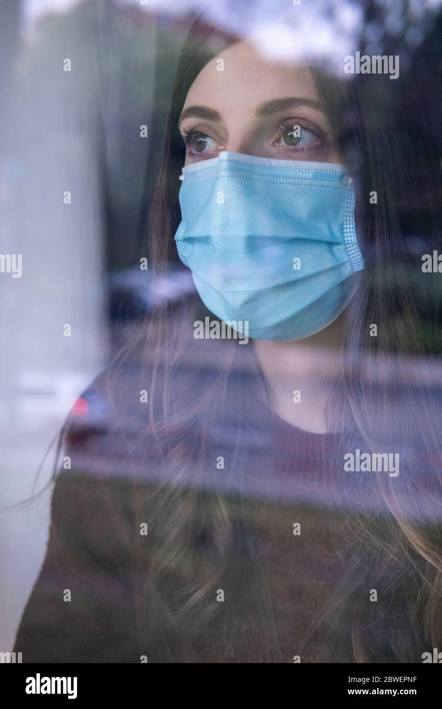 Young caucasian woman with nostalgic face looking out the window and ...