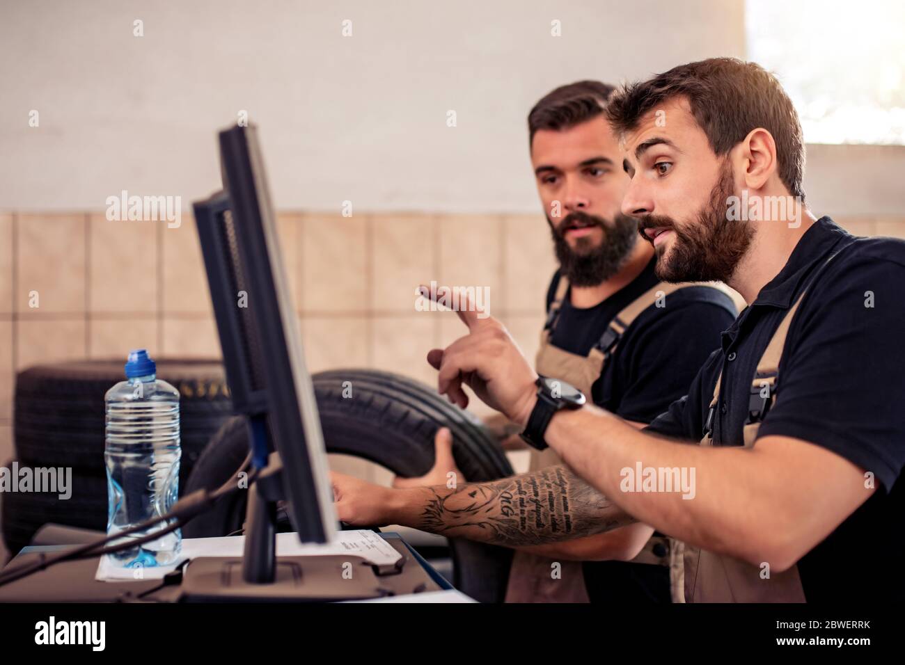 Teamwork. Mechanic holding a tire at the repair garage Stock Photo - Alamy