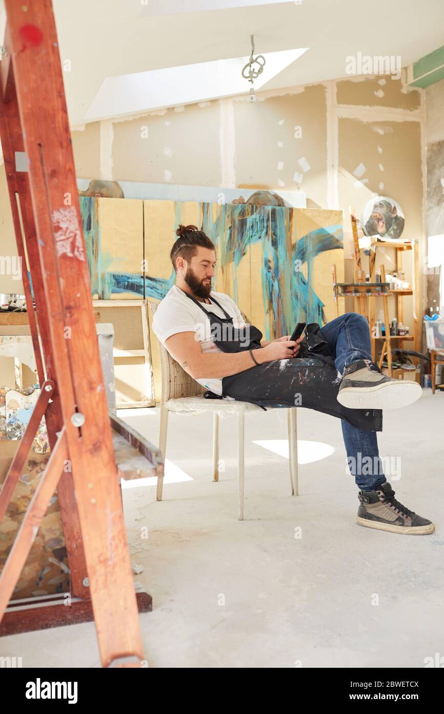 Vertical full length portrait of contemporary bearded artist using ...