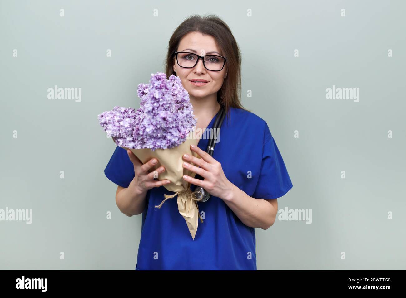 Doctor's Day, celebration. Happy smiling female medic with bouquet of ...