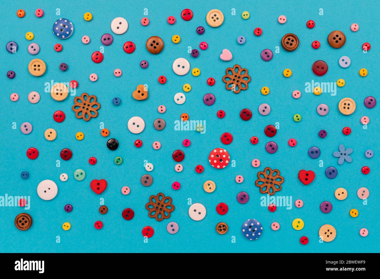 Multicolored buttons are scattered on the table. Top view with copy ...