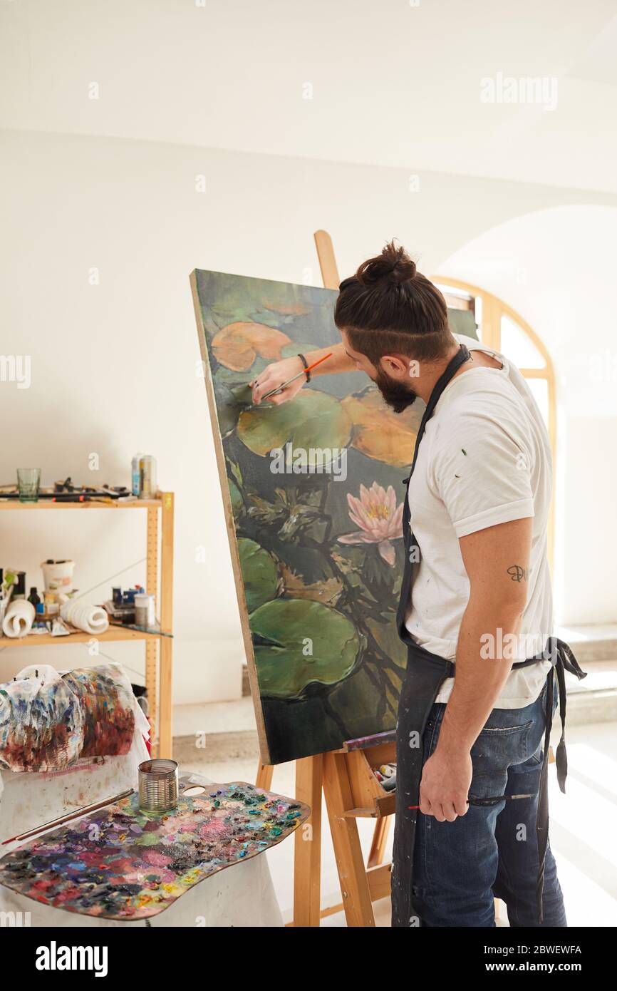 Vertical back view portrait of talented male artist painting picture on ...