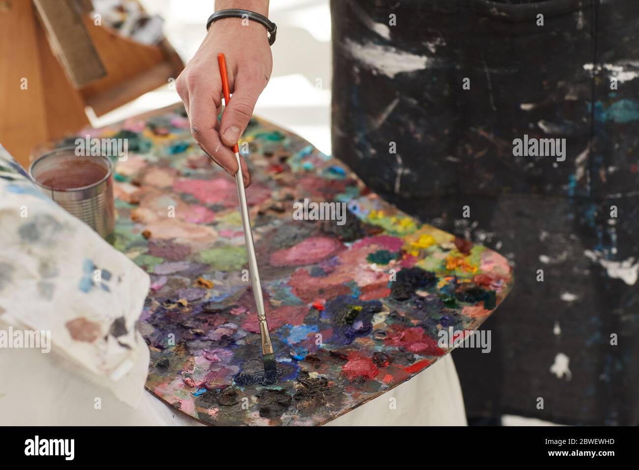 Close up of unrecognizable male artist mixing paint on palette while ...
