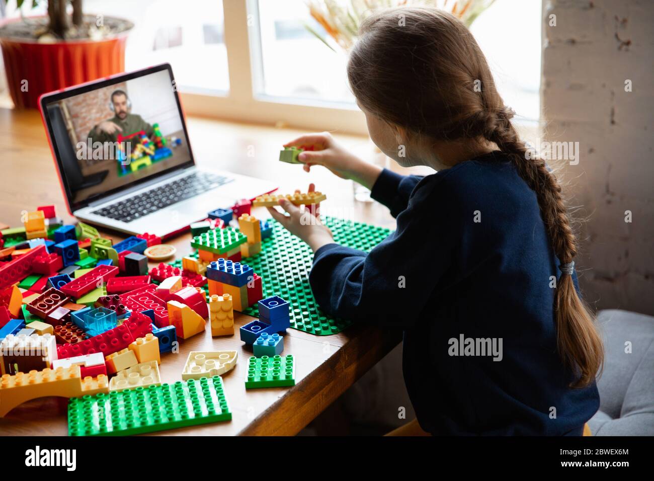 Girl playing with constructor at home, watching teacher's online ...