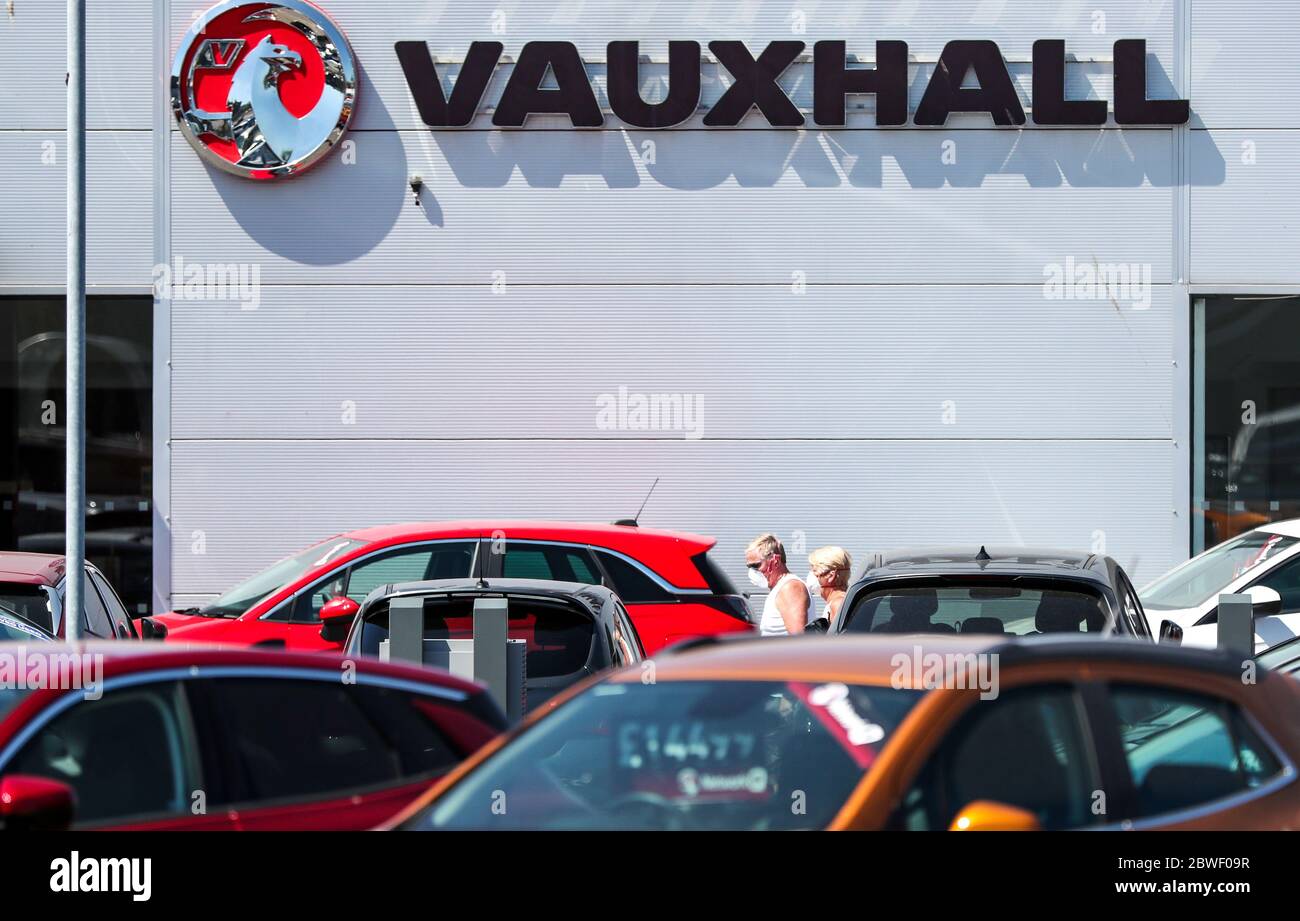 A couple walk past cars on forecourt vauxhall lookers hi-res stock ...