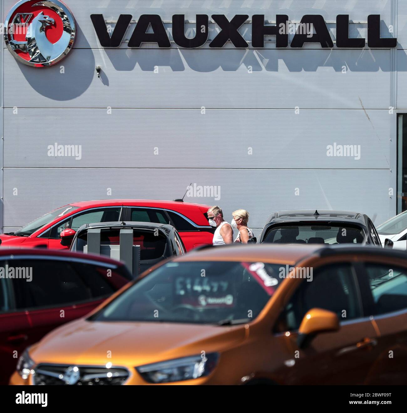 A couple walk past cars on forecourt vauxhall lookers hi-res stock ...