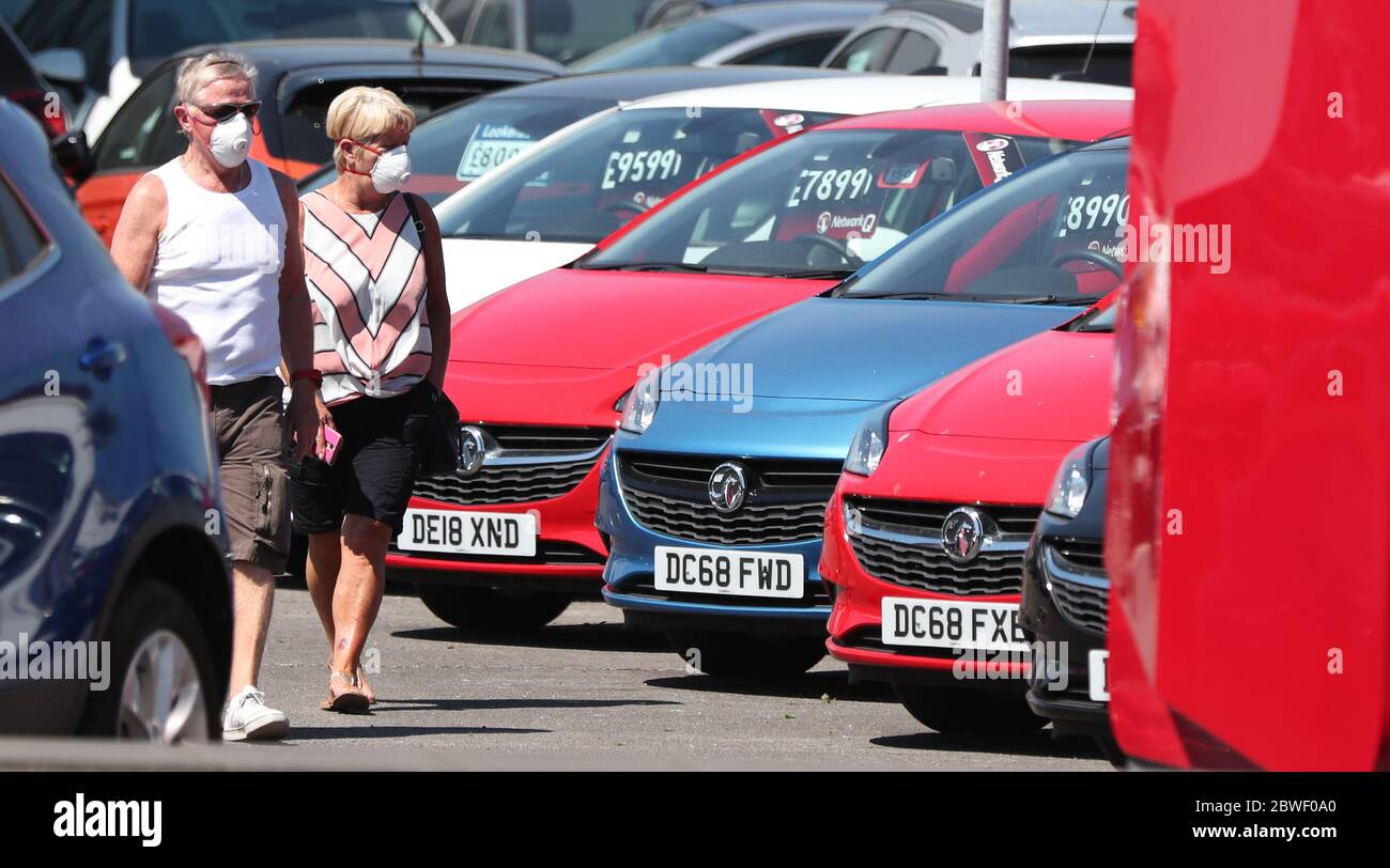 A couple walk past cars on forecourt vauxhall lookers hi-res stock ...