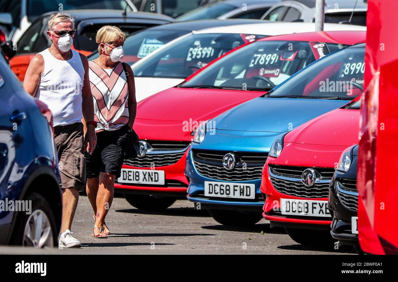 A couple walk past cars on forecourt vauxhall lookers hi-res stock ...