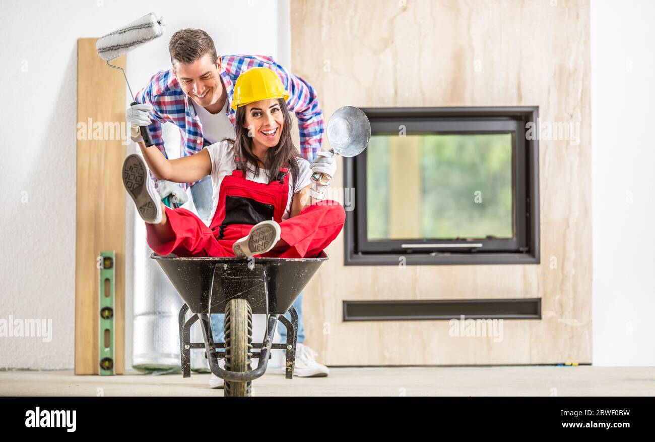 Happy couple having fun riding a wheelbarrow around the newly built ...