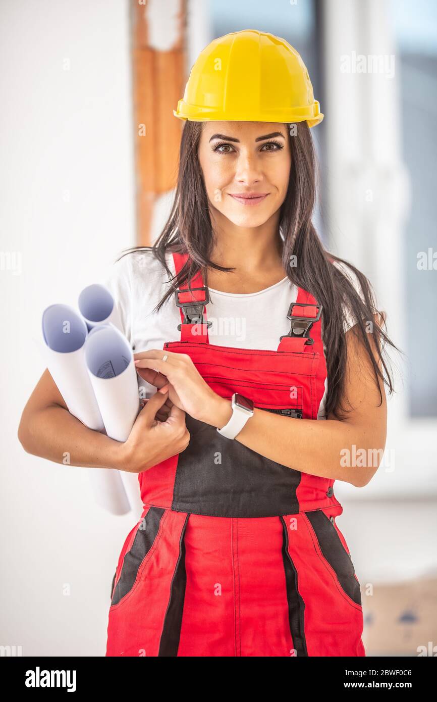 Good looking female construction planner holding blueprints dressed in ...