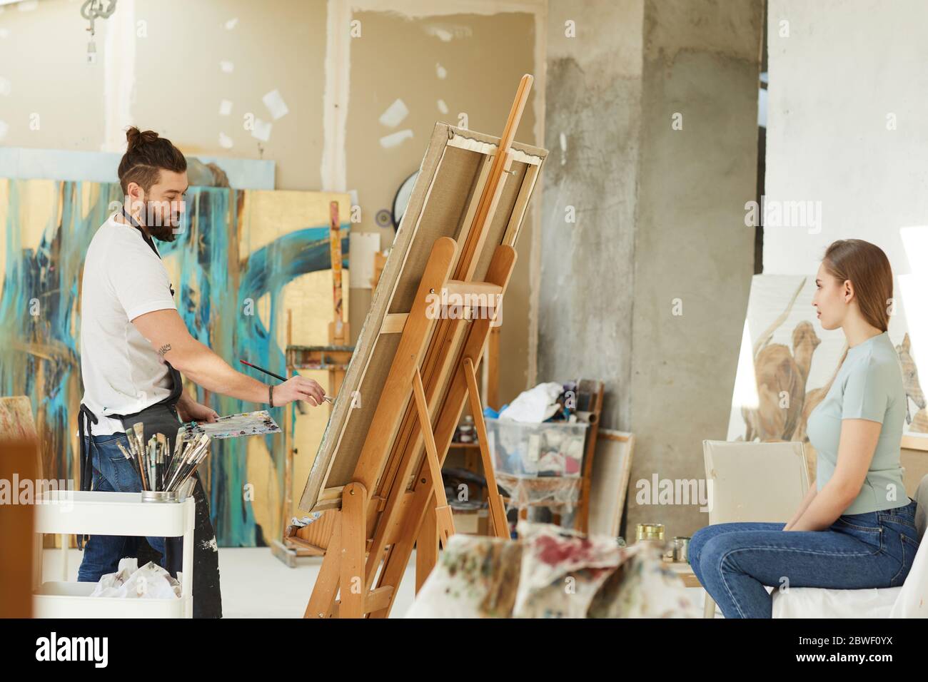 Side view portrai of male bearded artist painting portrait of young ...