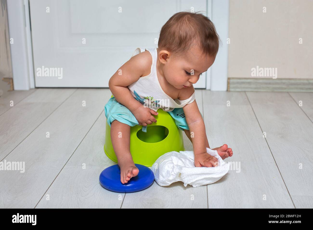 potty training concept. A cute little baby sits on a green pot and ...