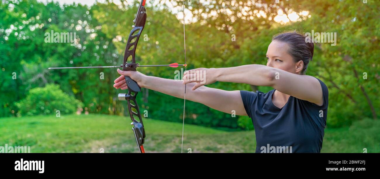 archery in nature, young woman aiming an arrow at a target Stock Photo ...