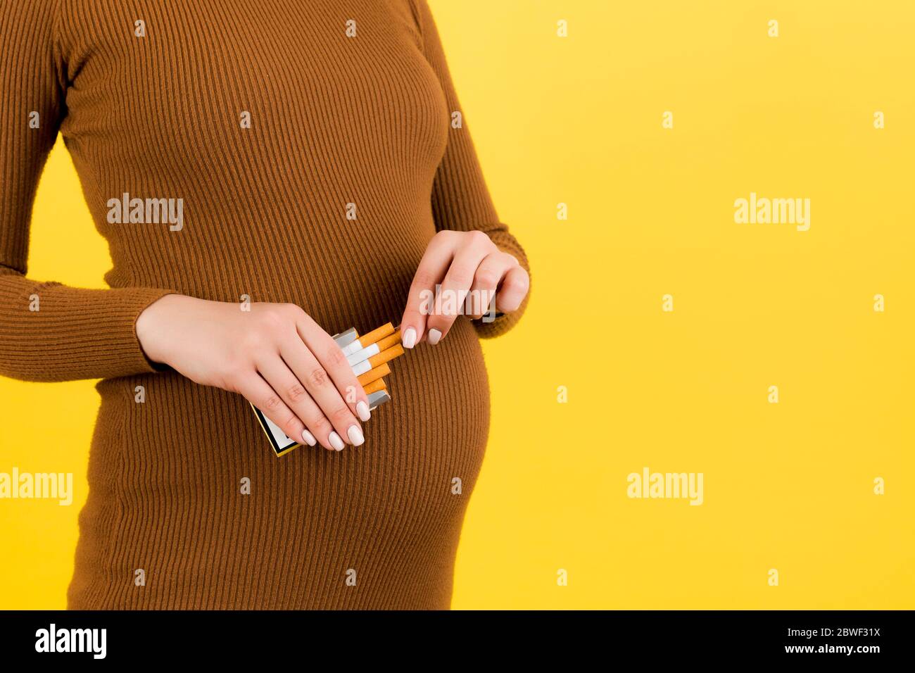 Close up of a pack of cigarettes in pregnant woman's hands at yellow ...