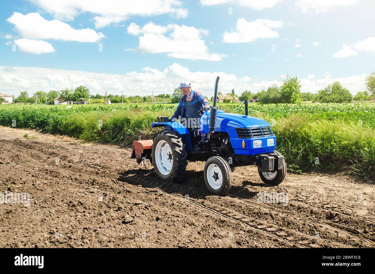 A farmer rides across the field on a tractor with a milling machine ...