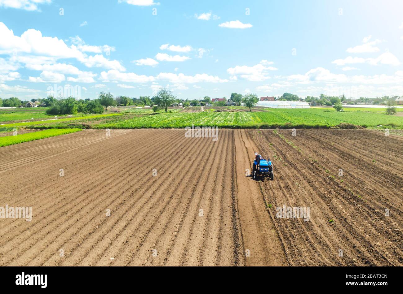 Farmer on tractor loosens and grinds the soil. Preparing the land for a ...