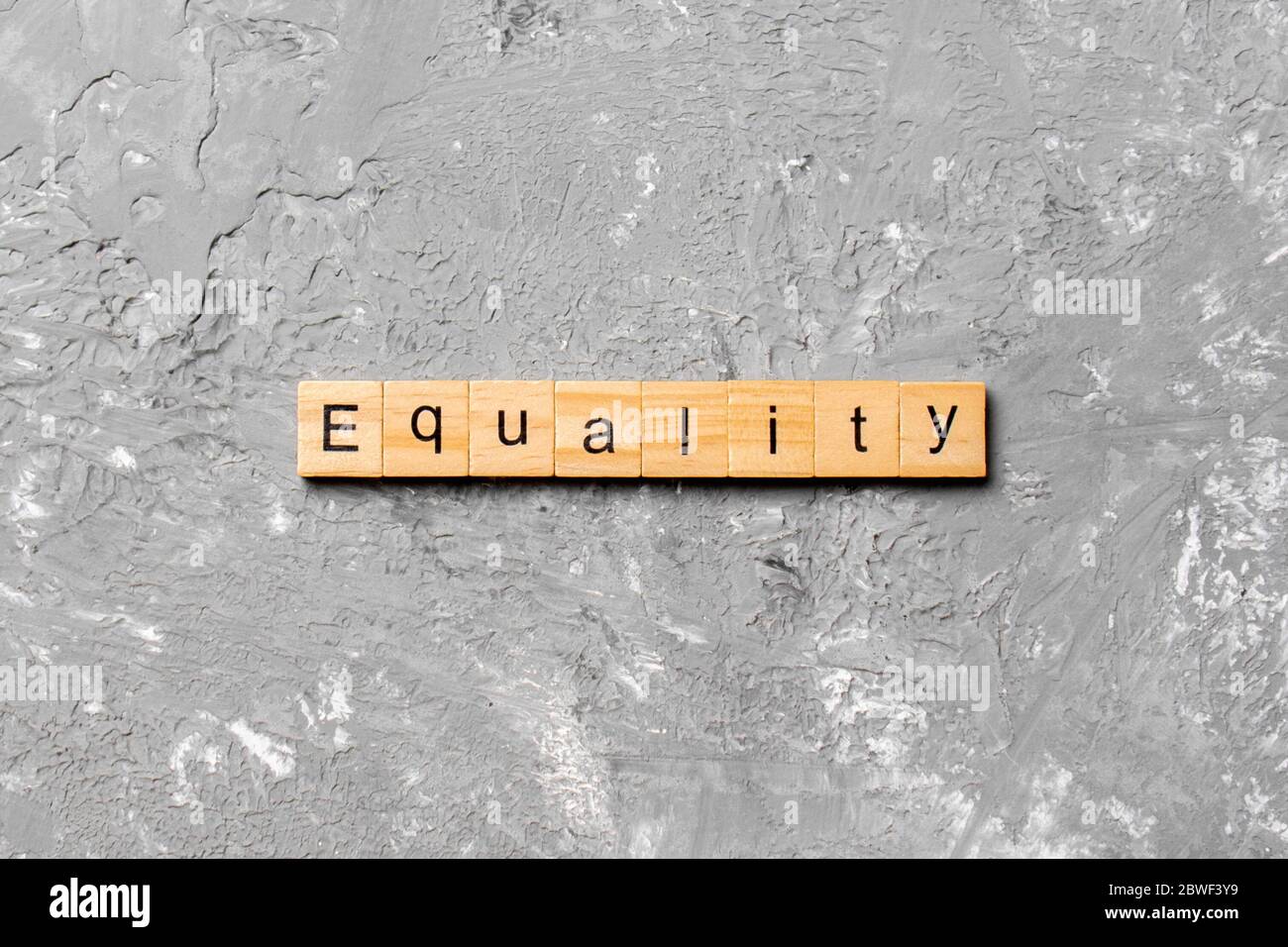 Equality word written on wood block. Equality text on cement table for ...