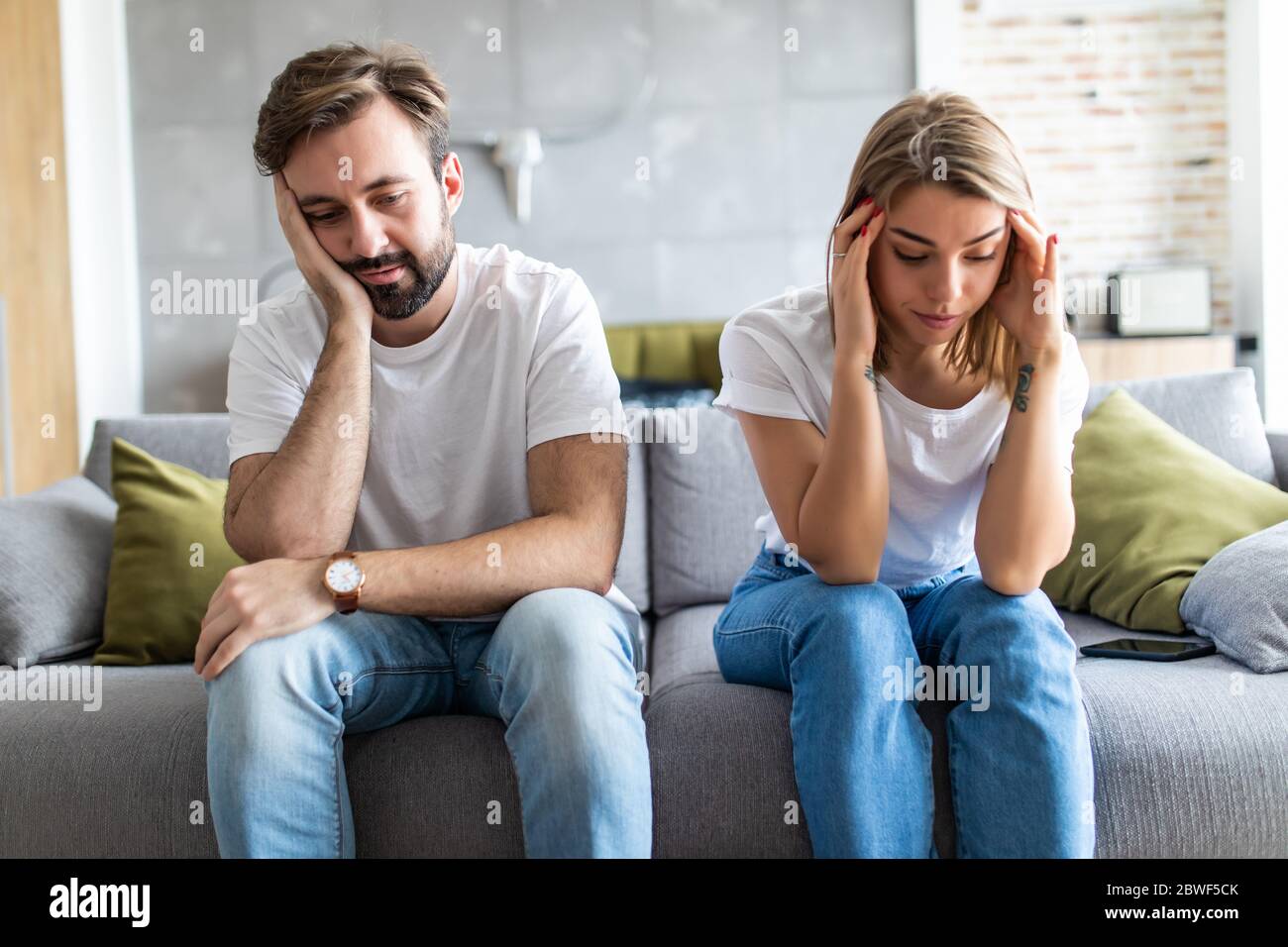 Portrait of frustrated couple are sitting on couch and are quarreling ...
