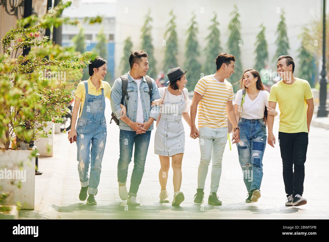 Happy positive friends laughing and joking around when walking in the ...