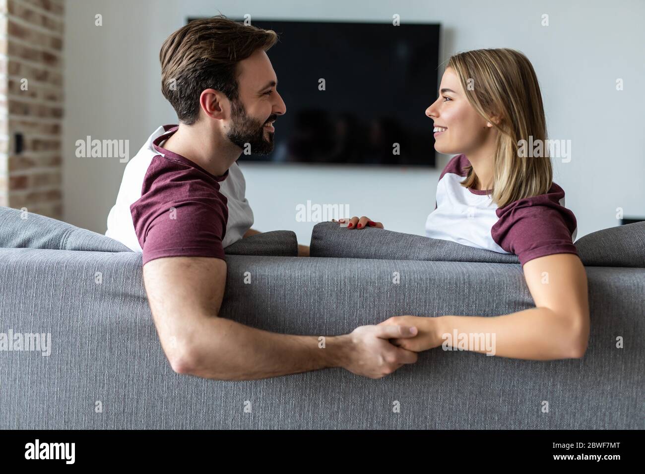 Young couple sitting on the couch holding hands each other Stock Photo ...