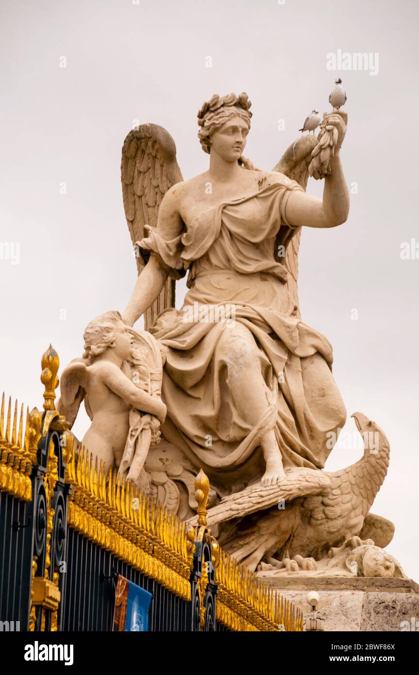 An angel resting, her foot on a bird statue at the gilded gate to the ...