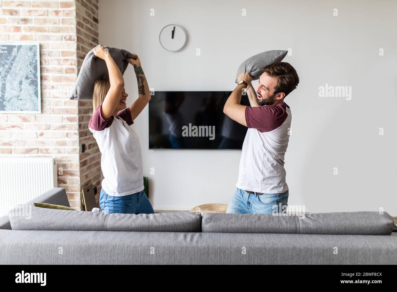 cheerful couple do a pillow battle on couch Stock Photo - Alamy