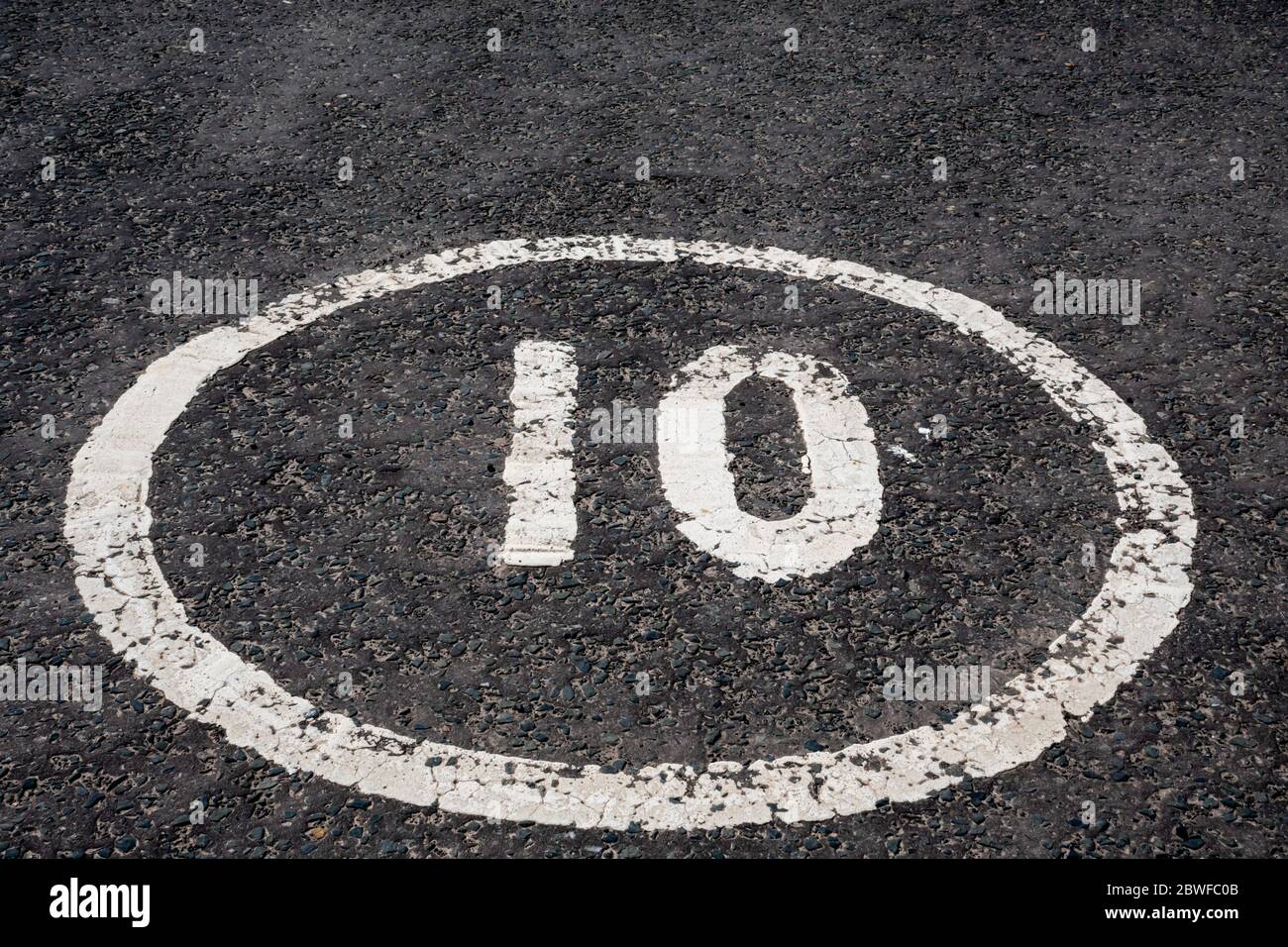 The number 10 speed limit inside a circle painted on a tarmac road ...