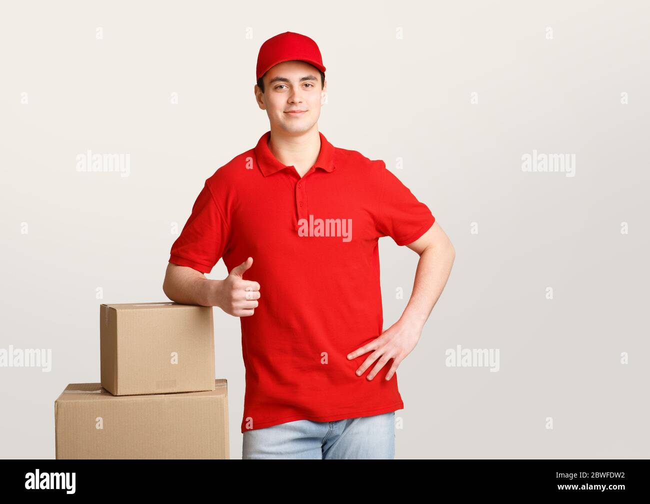 Fast delivery. Courier leans on boxes and shows sign perfectly with his ...