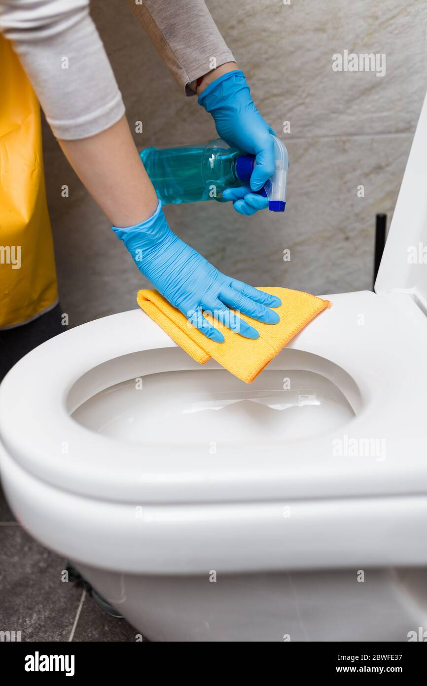 Close up of female hands in rubber gloves cleaning toilet bowl with ...