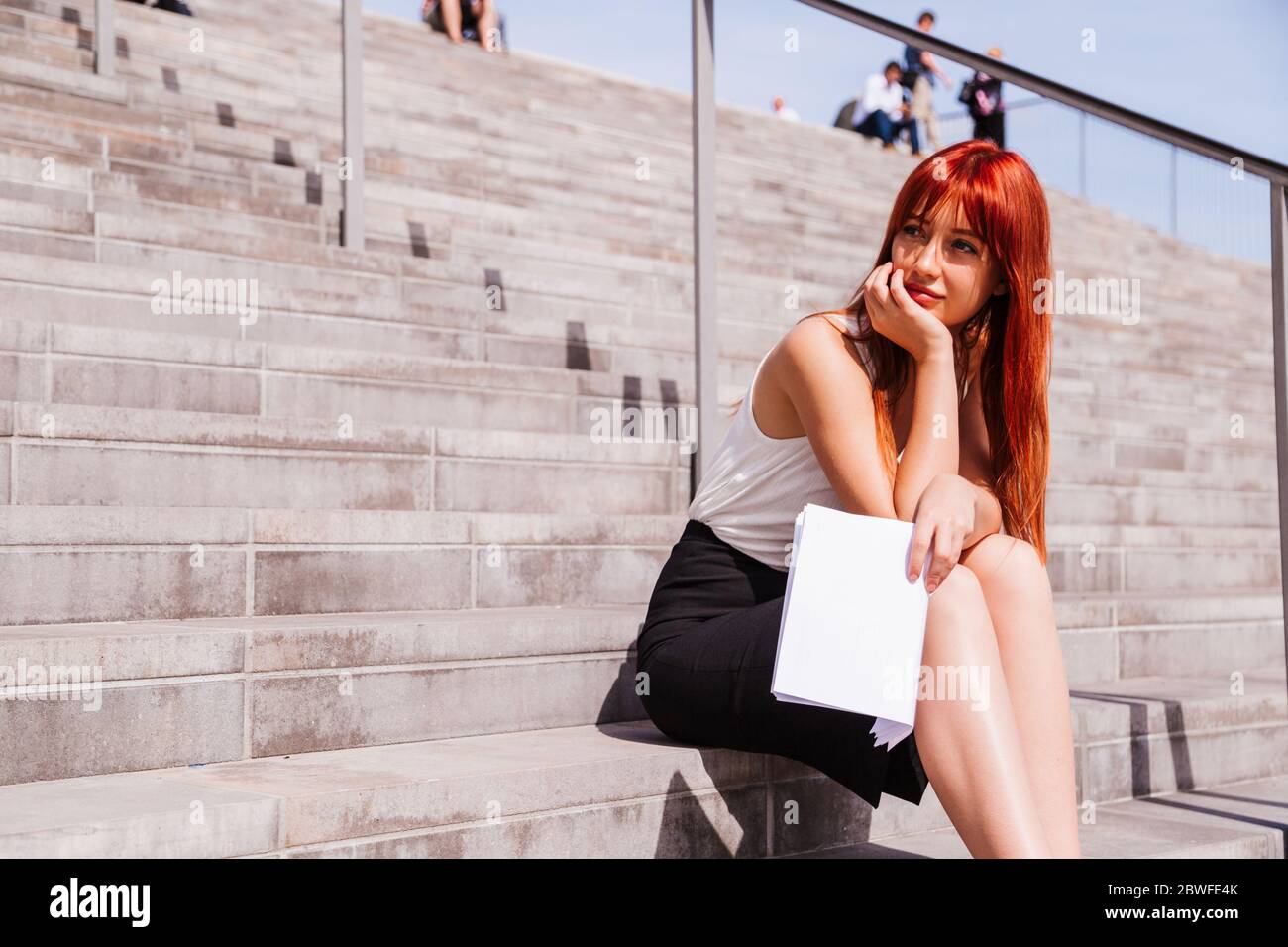 Young girl sits on stairs and holds paper forms Stock Photo - Alamy