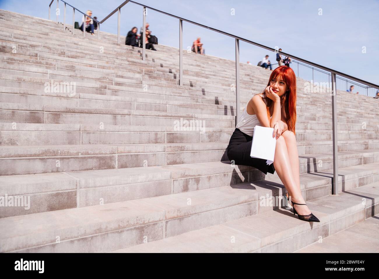 Young girl sits on stairs and holds paper forms Stock Photo - Alamy