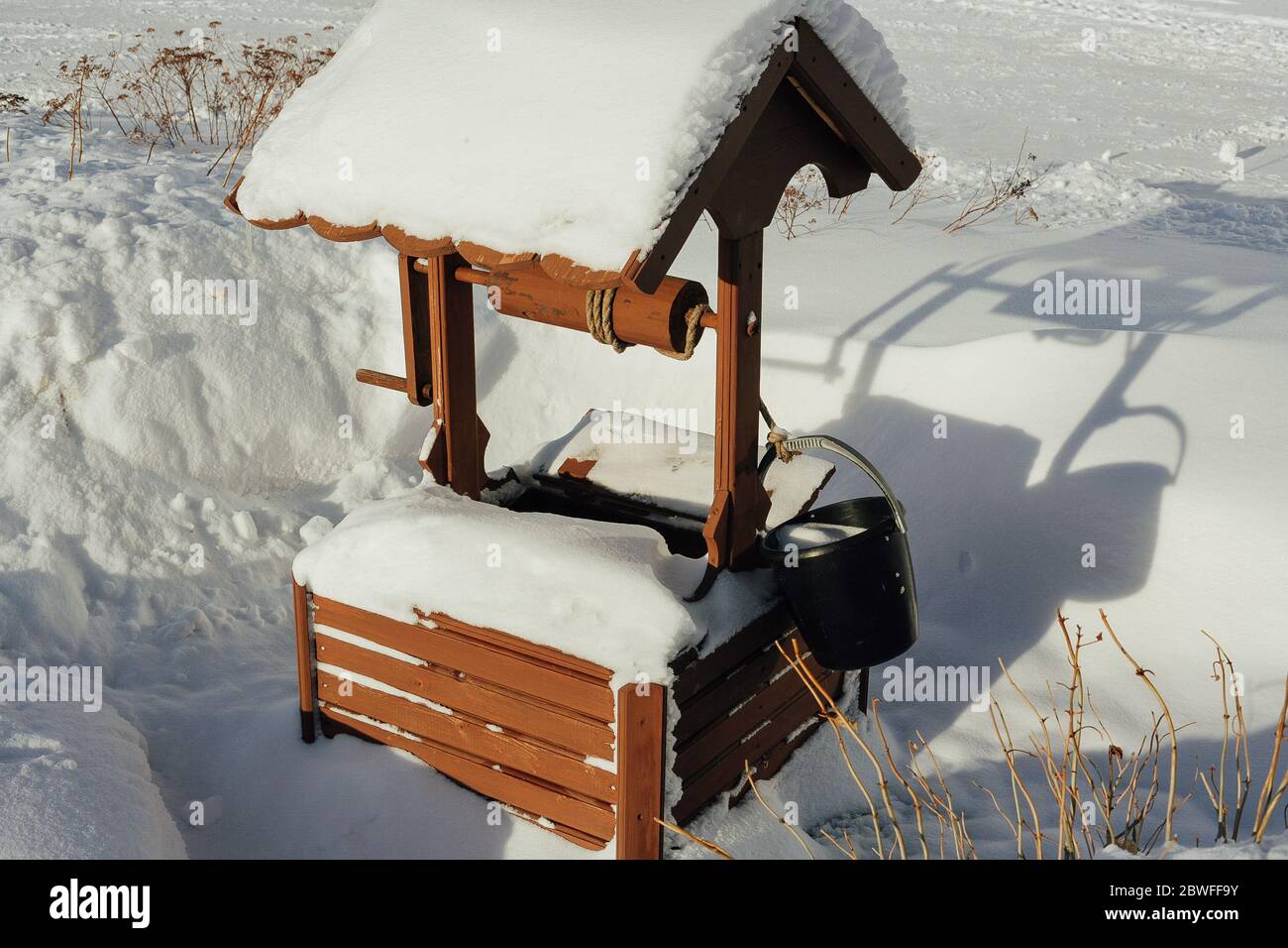 Winter village landscape. Wooden well with a winch in the snowdrifts ...