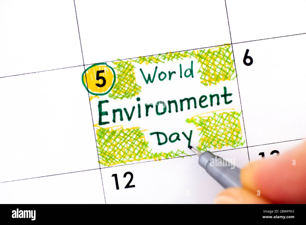 Woman fingers with pen writing reminder World Environment Day in ...