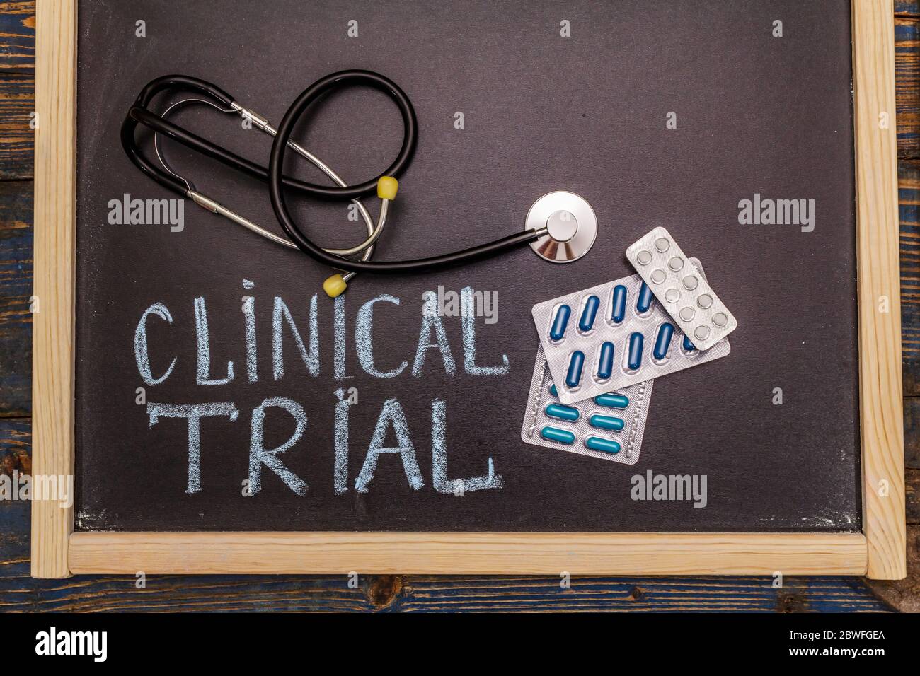 Clinical trial concept. Chalk board, stethoscope, pills. Wooden boards ...