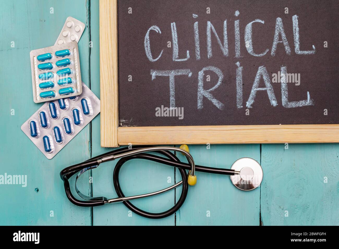 Clinical trial concept. Chalk board, stethoscope, pills. Wooden boards ...