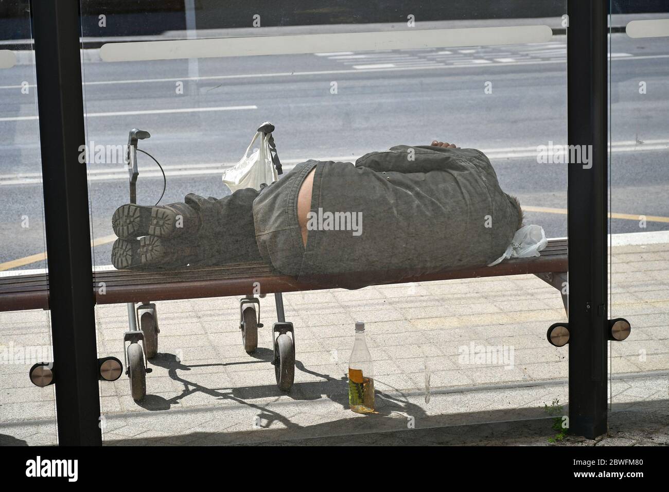 Homeless man is sleeping on a bench at the bus stop Stock Photo - Alamy