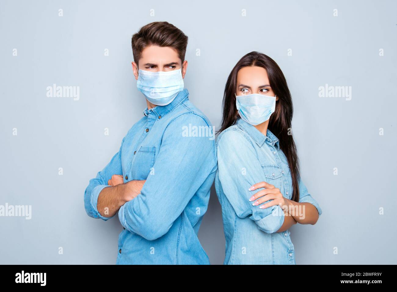 Serious man and woman with crossed hands standing back to back after ...