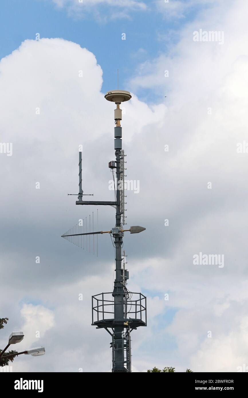 Cellular, mobile phone transmitter tower and weather station with blue sky and clouds middle ...