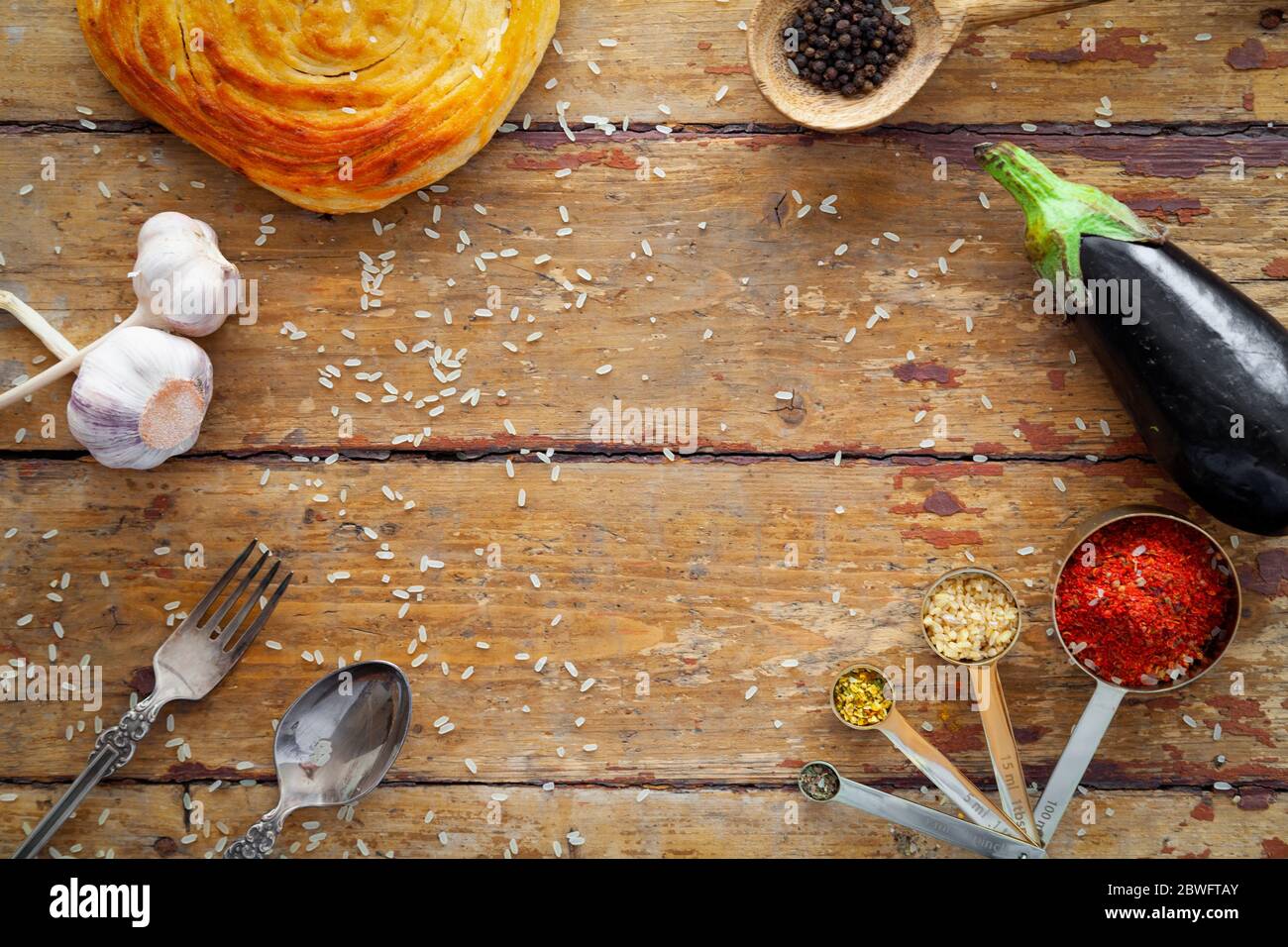 Pilaf ingredients, rice, vegetables, pita, cutlery, spices on rustic ...
