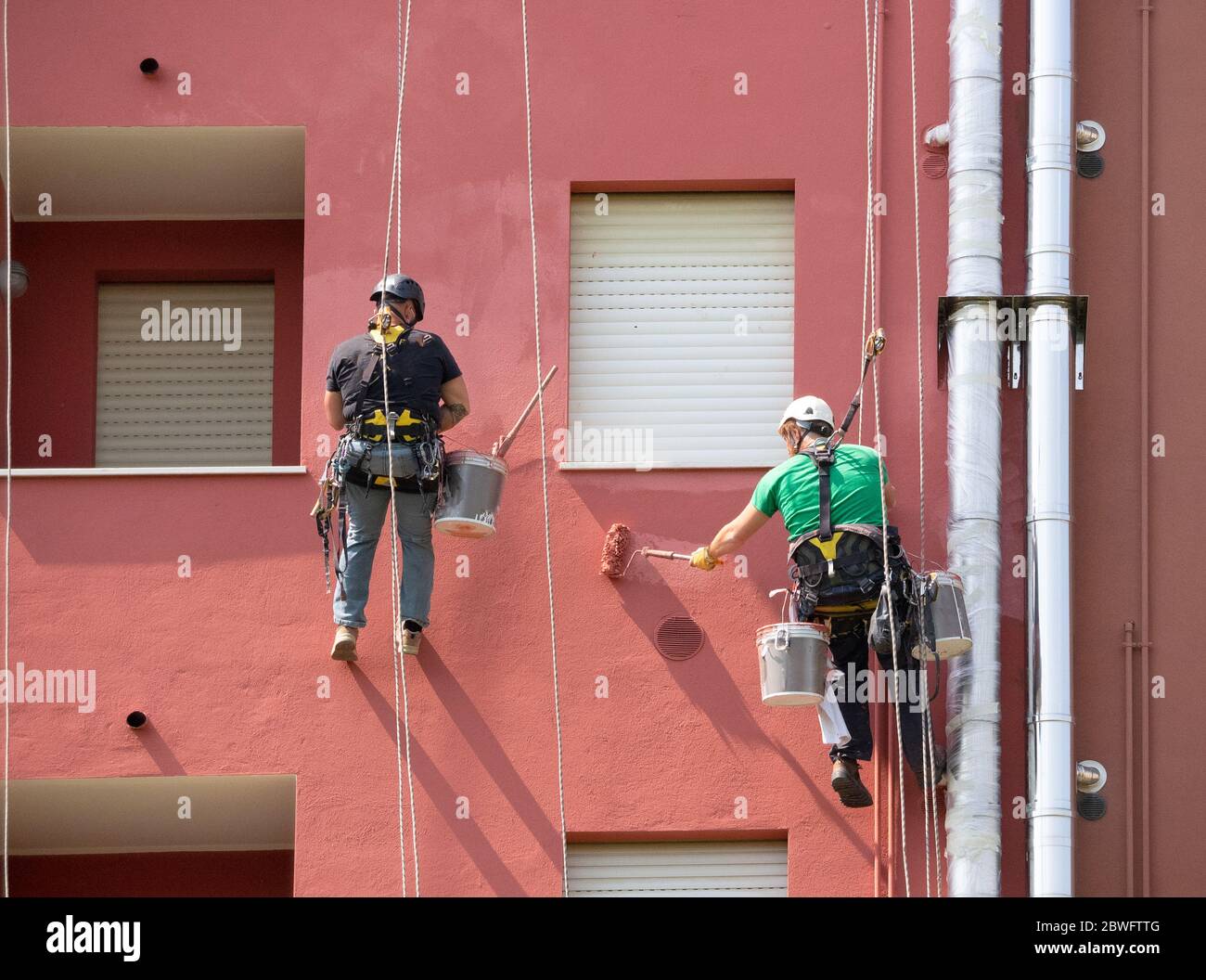 painting of building facade by worker suspended with a rope Stock Photo ...