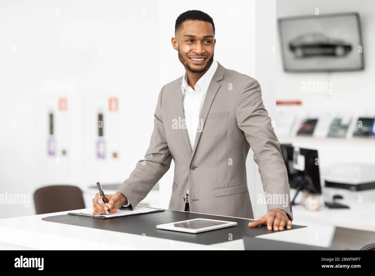 Auto Dealer Standing At Counter Working In Dealership Office Stock ...