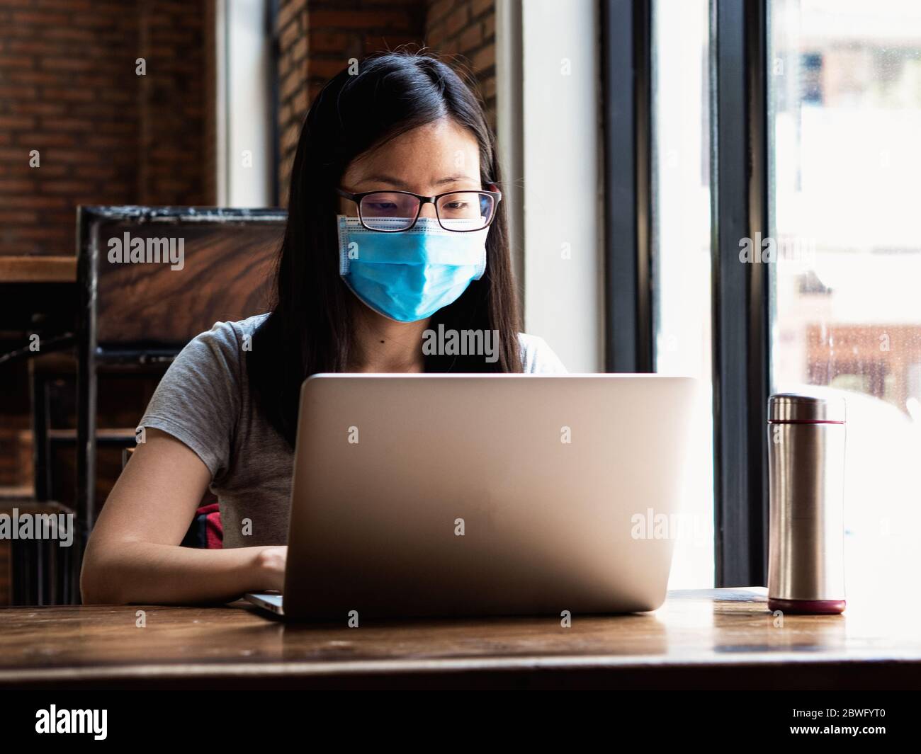 New normal, programmer wearing mask working remotely in cafe during ...