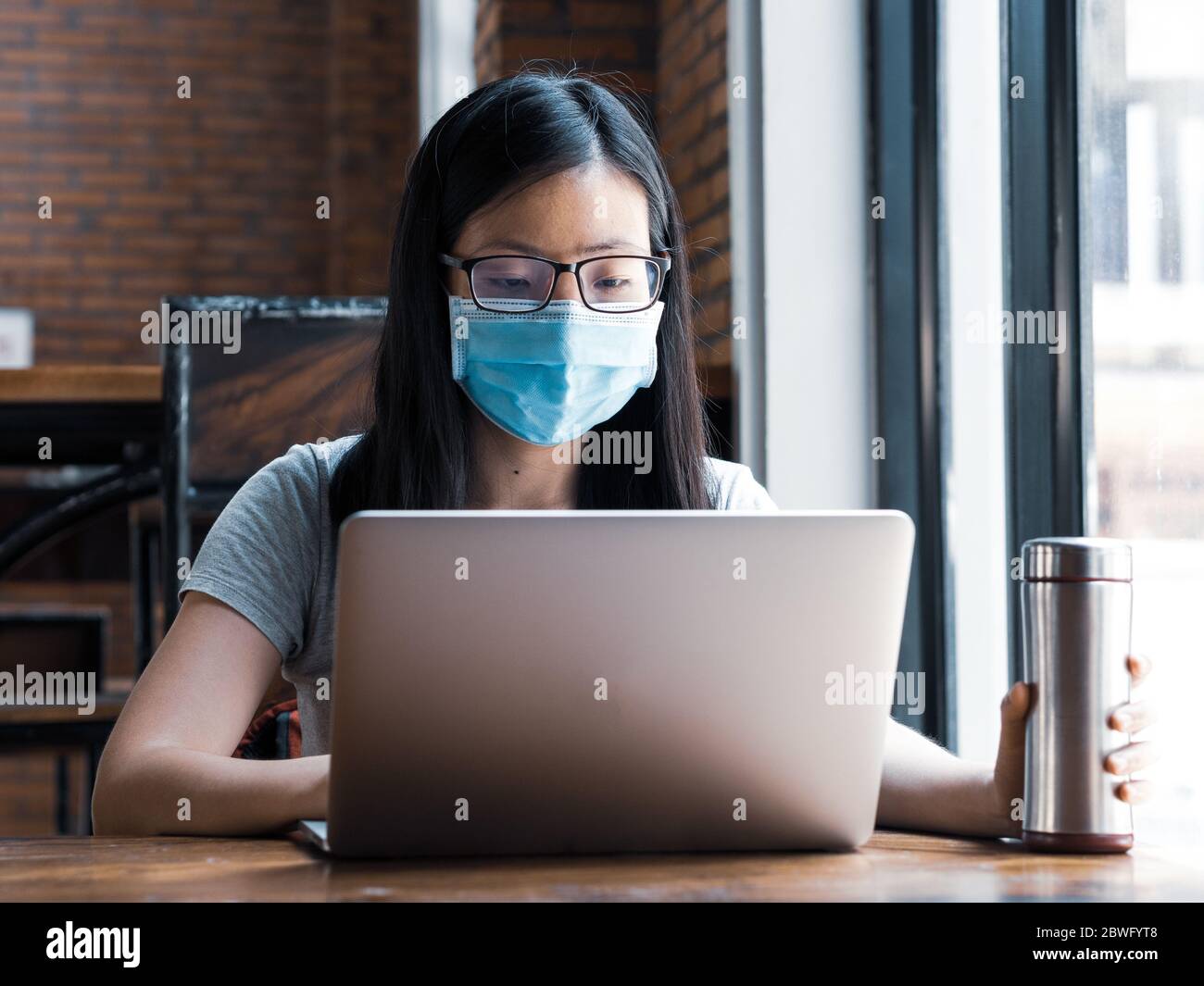 New normal, programmer wearing mask working remotely in cafe during ...