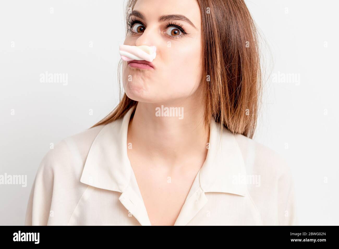 Young woman making mustache with sweet candy marshmallow on white ...