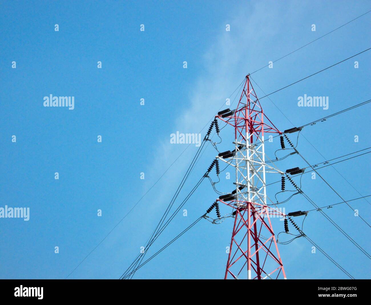The high voltage transmission towers are red and white on the blue sky ...