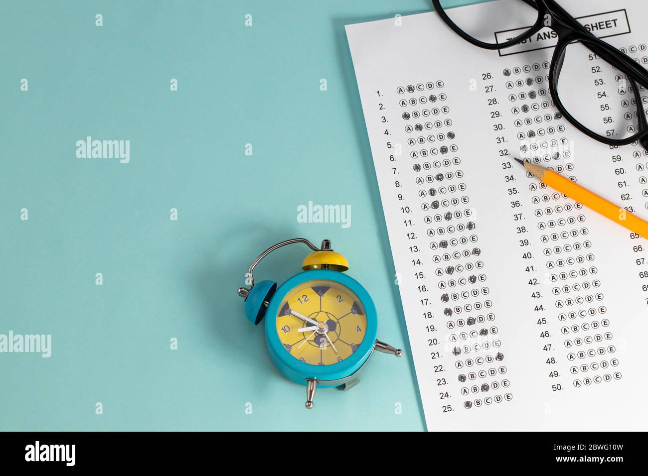 Take the exam, write the exam. Exam paper with alarm clock on blue ...