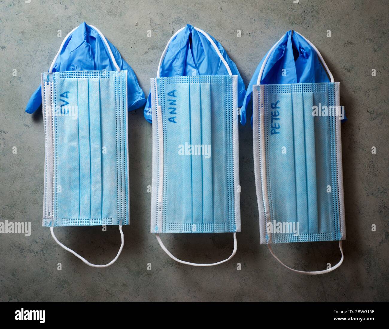 Surgical masks and gloves in a wall with the names of the users written ...
