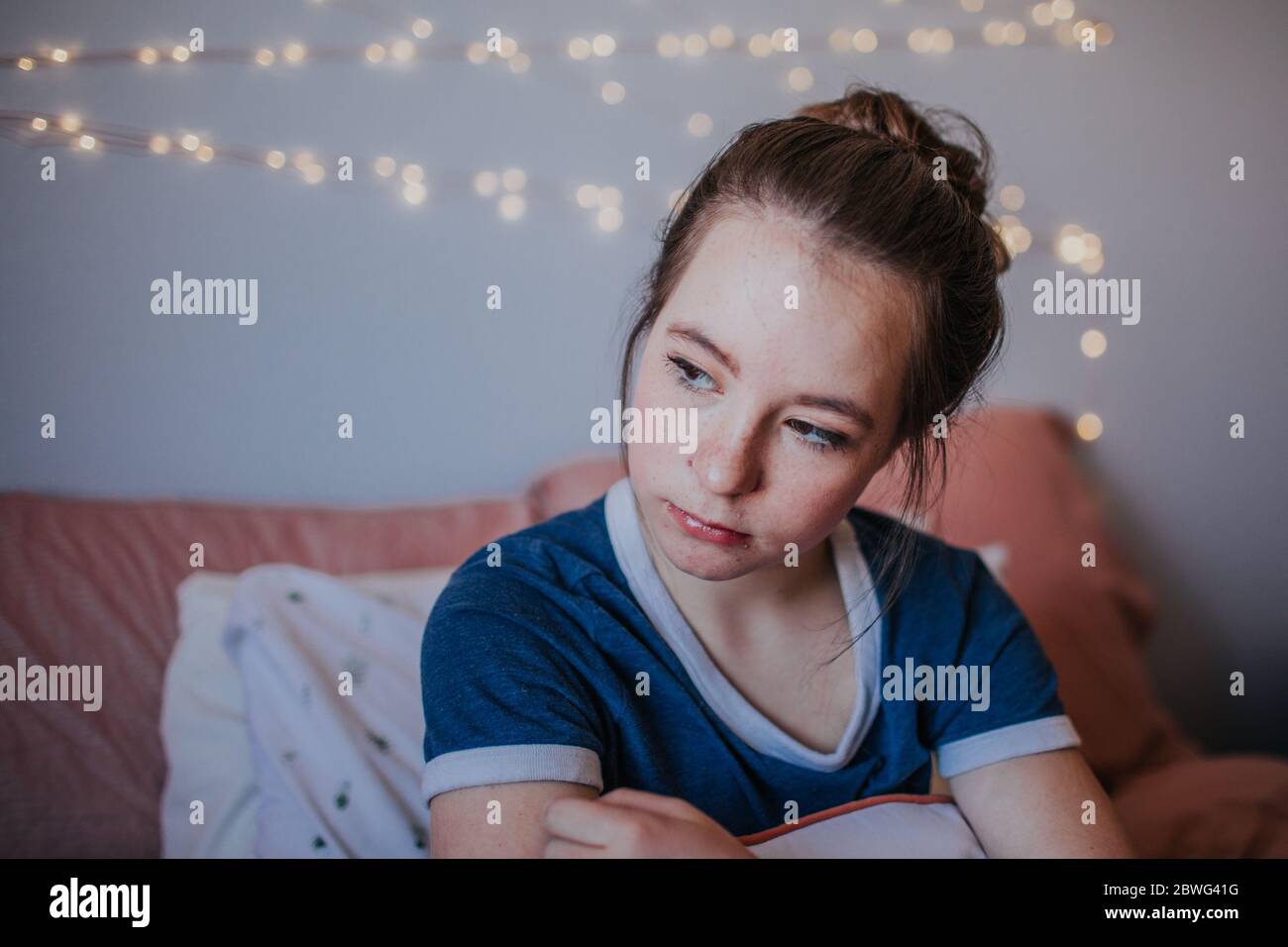 portrait of tween girl sitting on bed looking away Stock Photo - Alamy