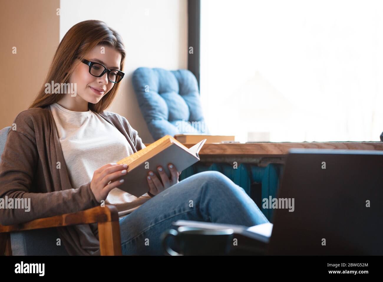 Young girl sitting near window sill and reading a book Stock Photo - Alamy