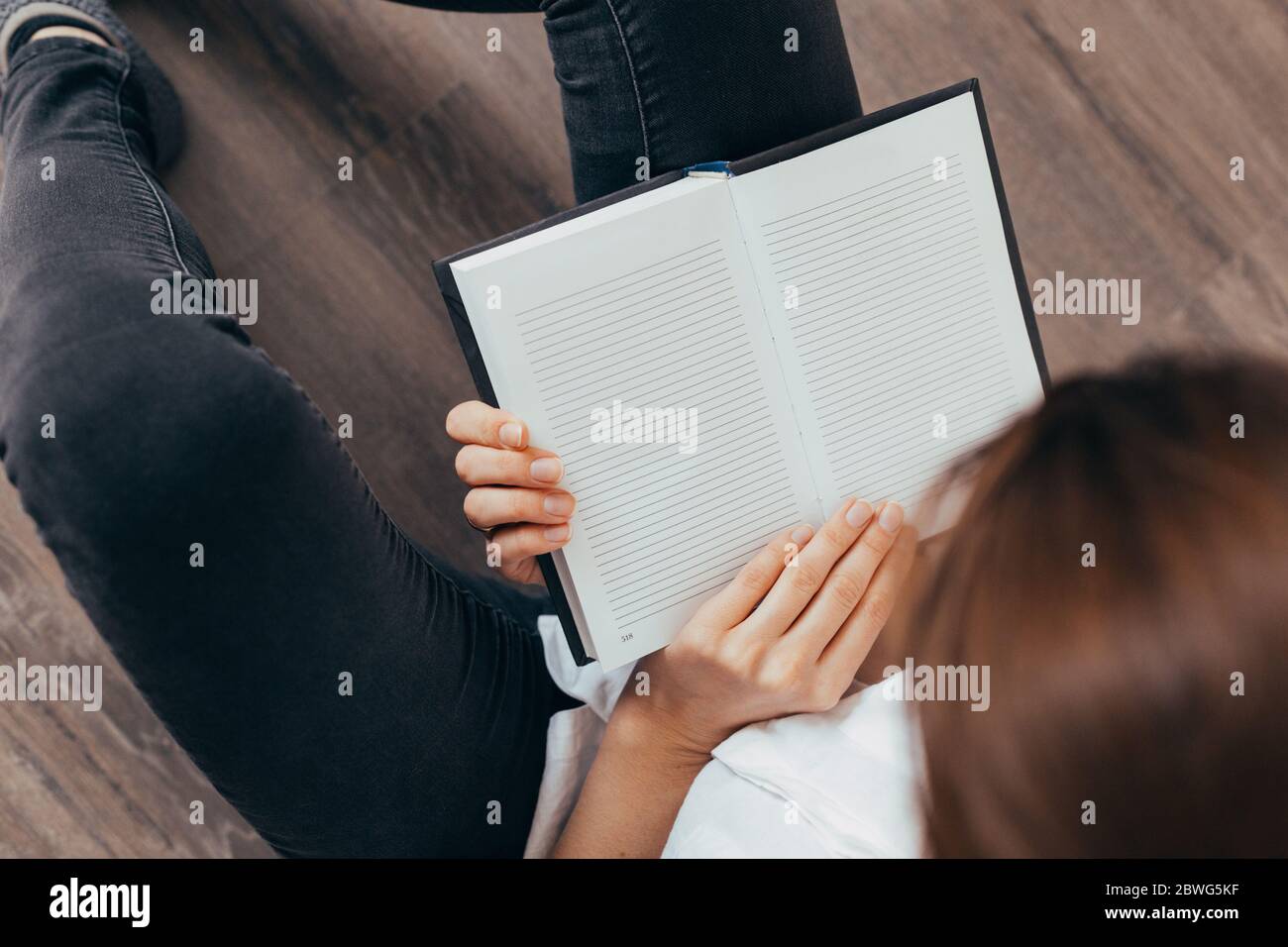 Beautiful female hands hold an open book or magazine in a room sitting ...